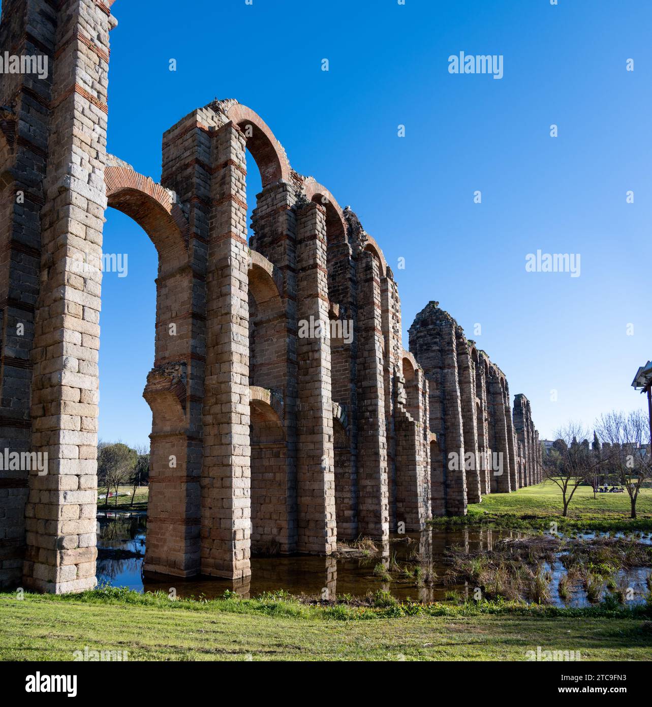 Ancient Roman aqueduct with arches under a clear blue sky, reflecting ...