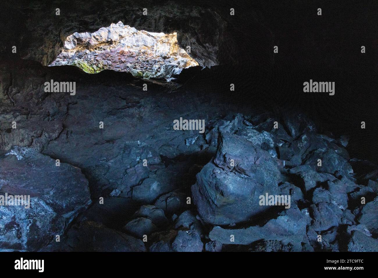 A cave opening in Indian Tunnel rising above rocks along the cave floor ...
