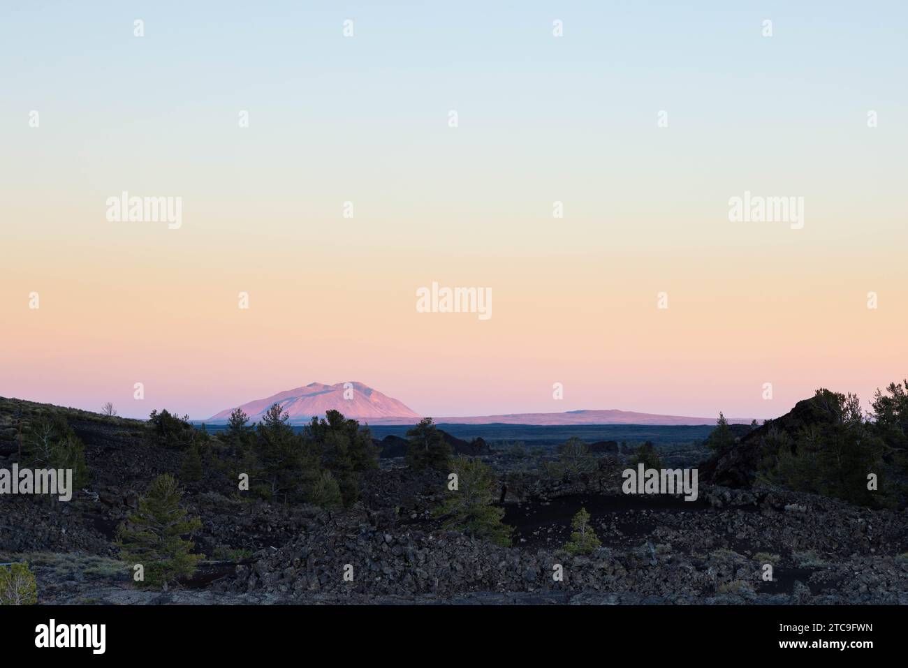 Big Southern Butte rising high in the distance beyond a lava field ...
