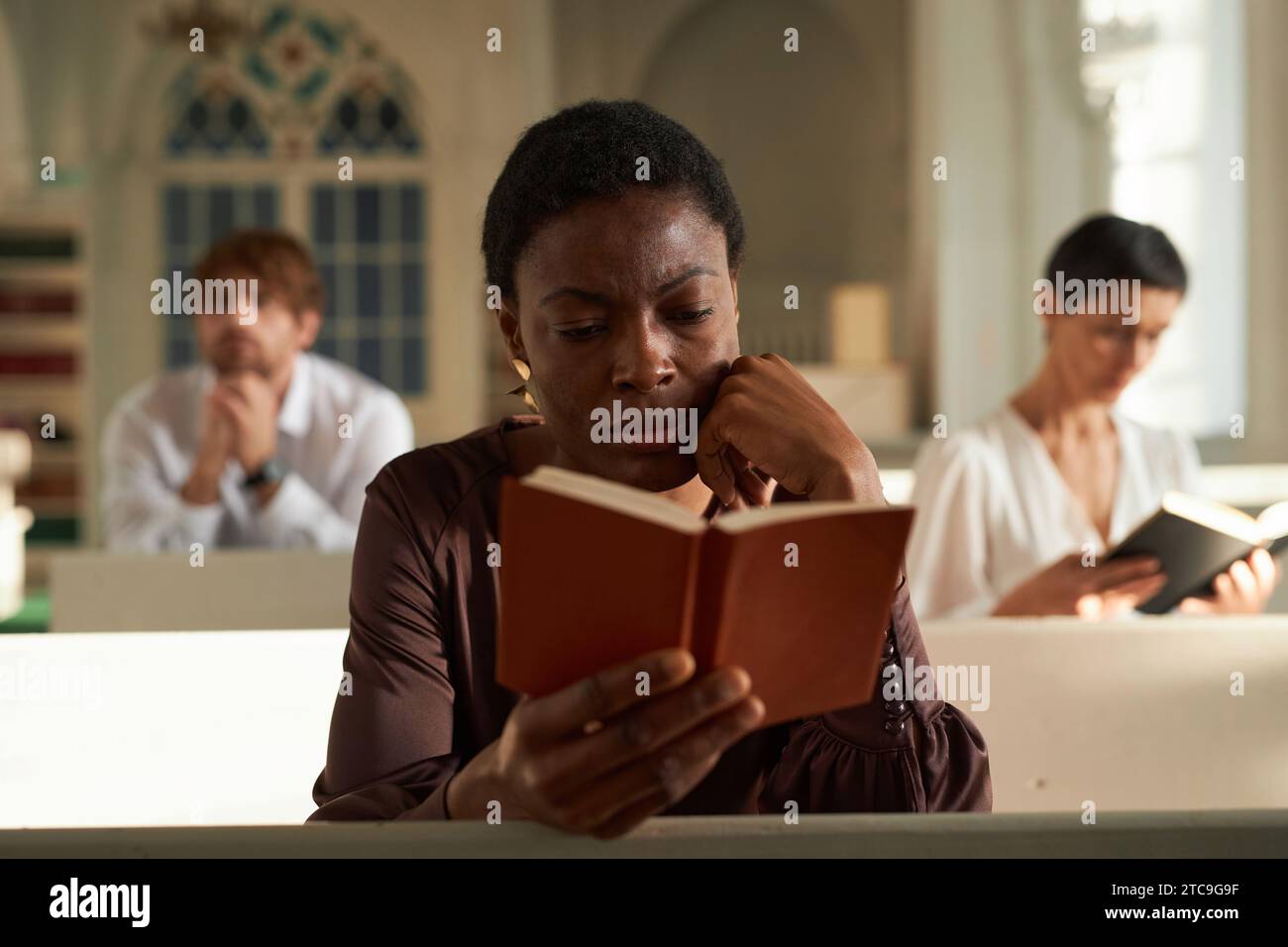 Portrait of adult African American woman reading Bible in church on ...