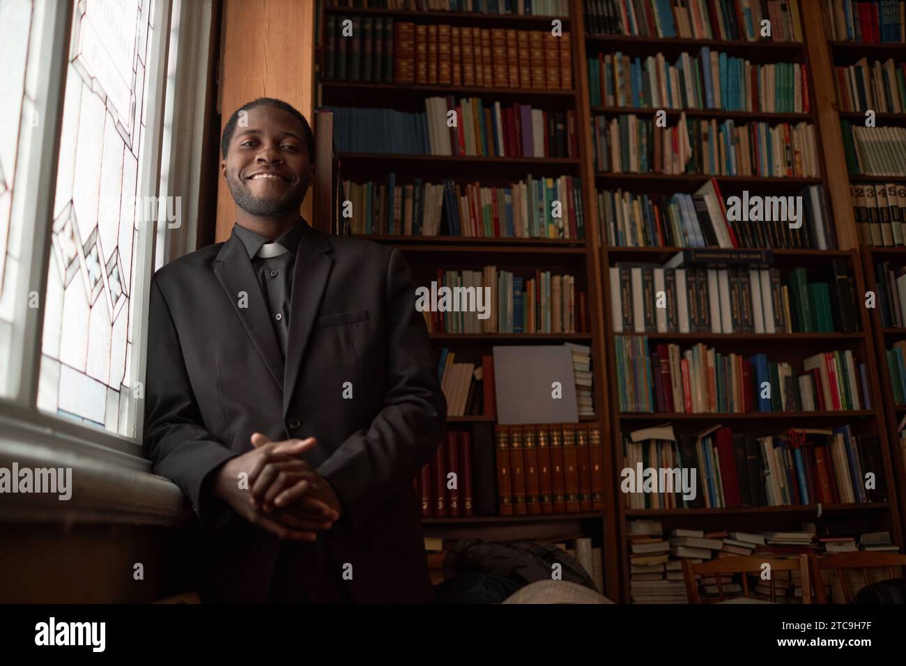 Portrait of smiling Black man as pastor looking at camera posing by ...
