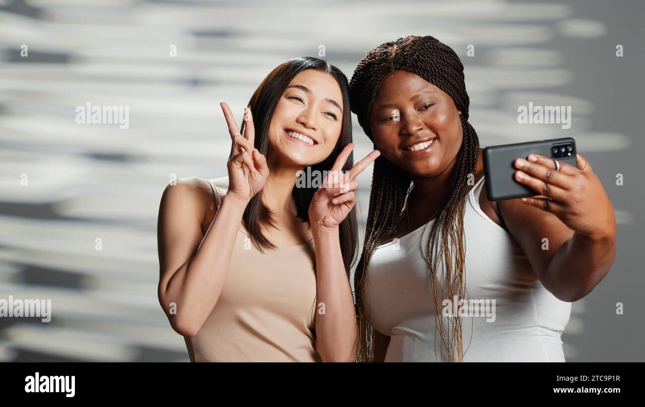 Interracial confident girls taking pictures on smartphone, having fun ...