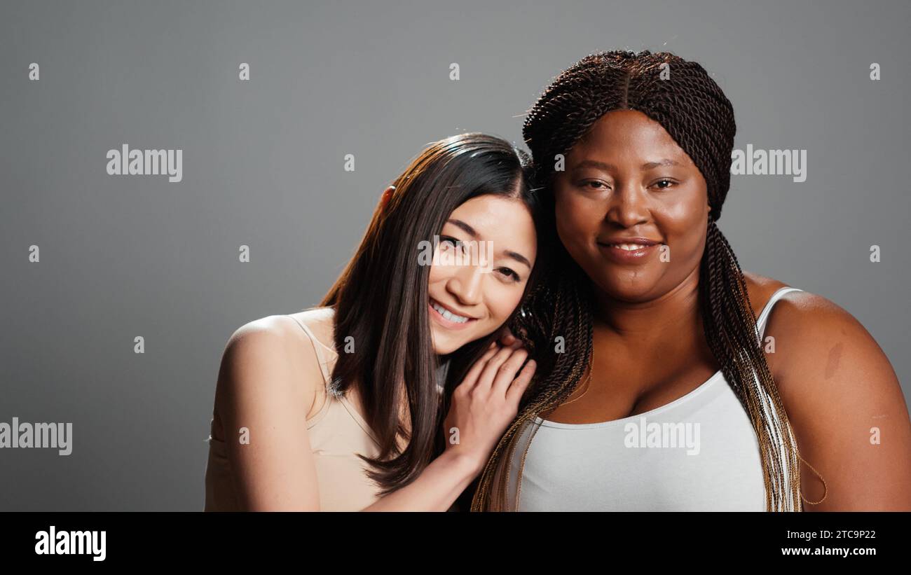 Cheerful diverse models laughing and hugging in studio, enjoying ...