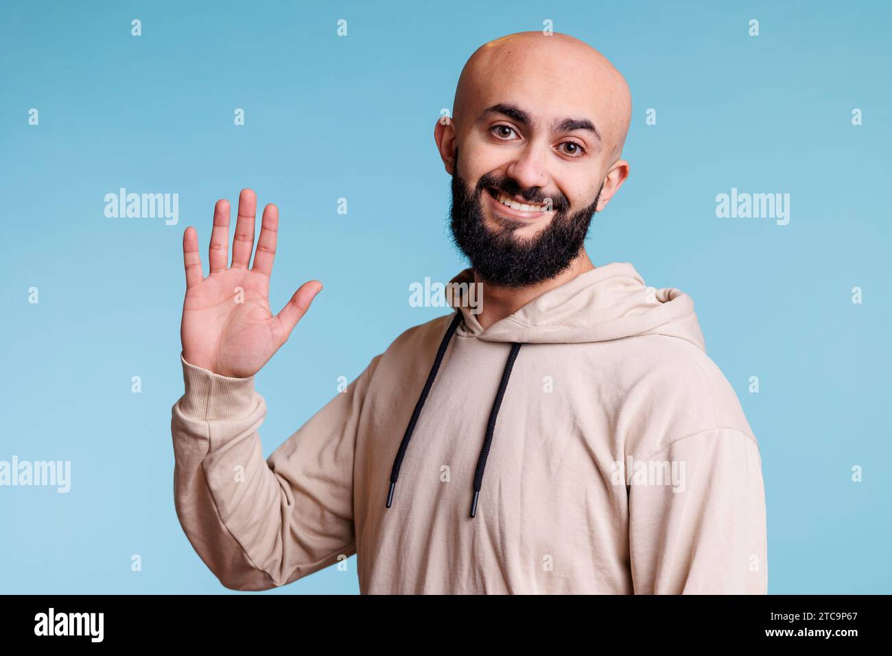 Cheerful arab man waving hi with hand and looking at camera. Happy ...