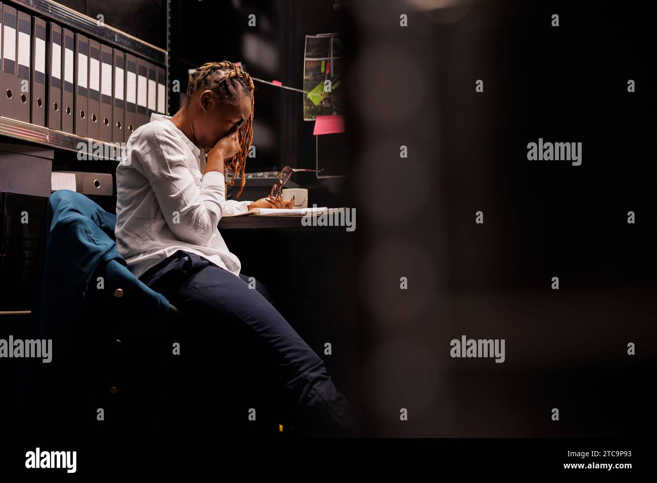 Exhausted police investigator working overtime and rubbing eyes while ...