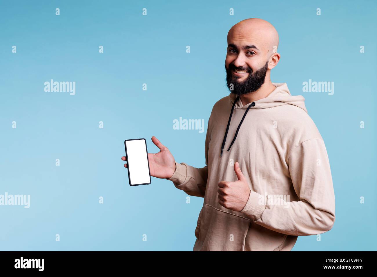 Smiling arab man advertising app on touchscreen smartphone, displaying ...