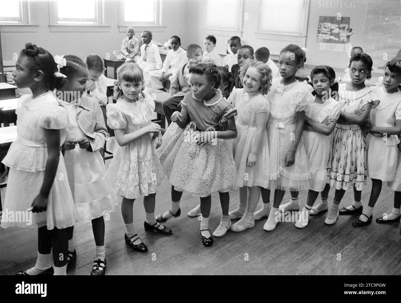 Racially integrated classroom of young girls in a row with boys sitting ...