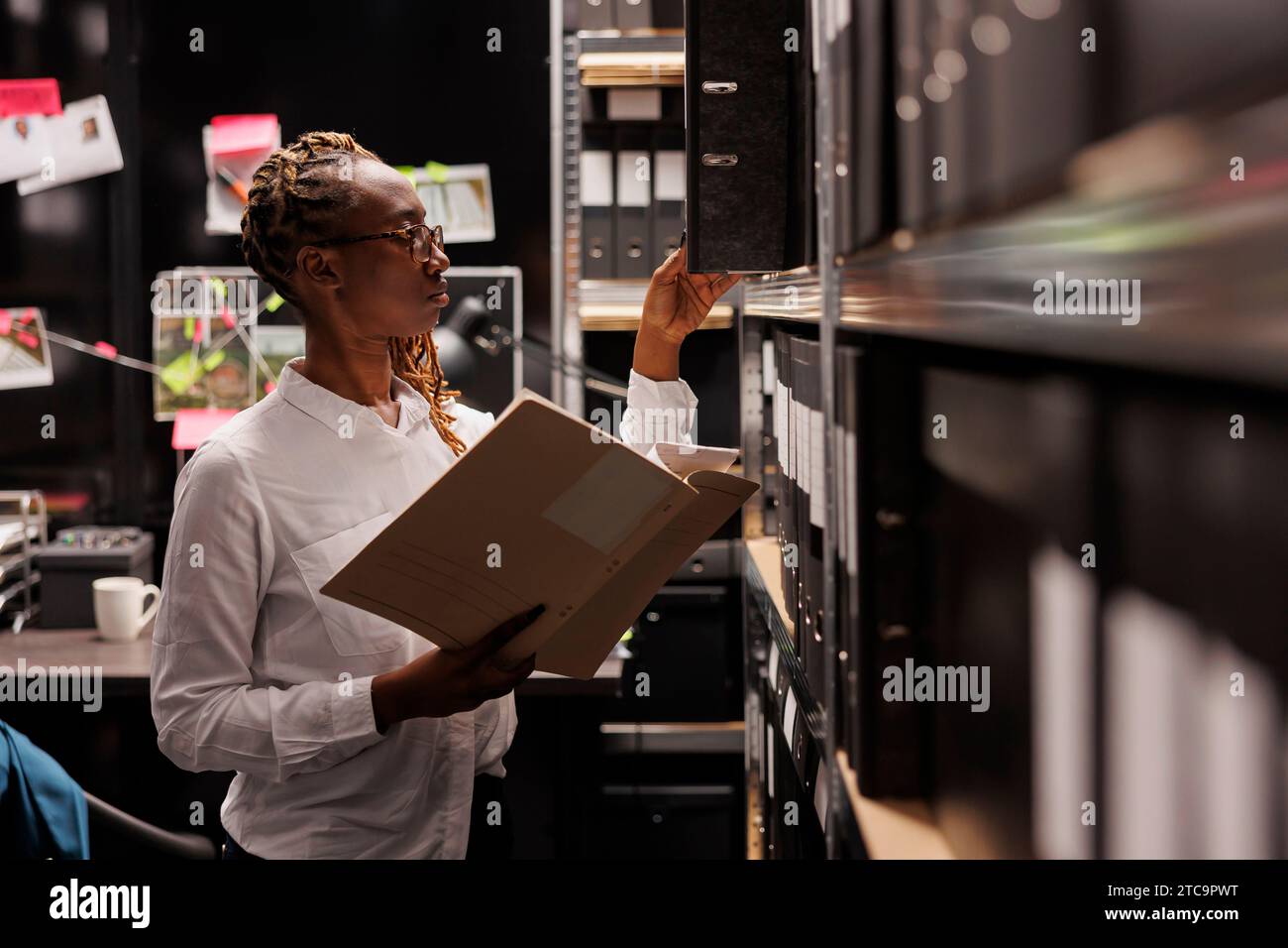 Police investigator studying archival crime case materials, working ...
