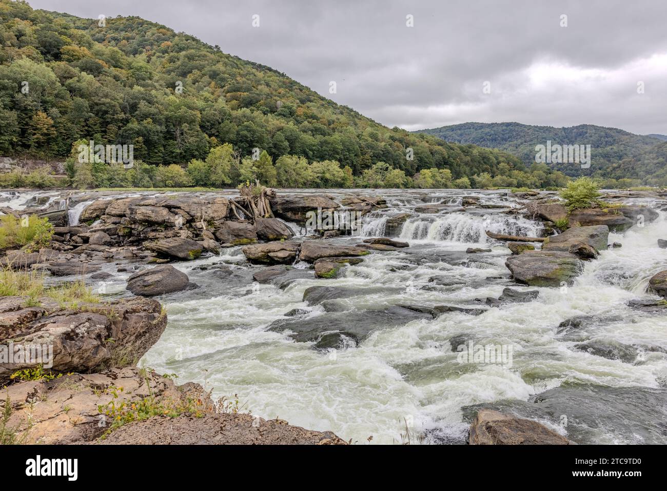 A majestic river winds through a verdant hillside beneath a mountain ...