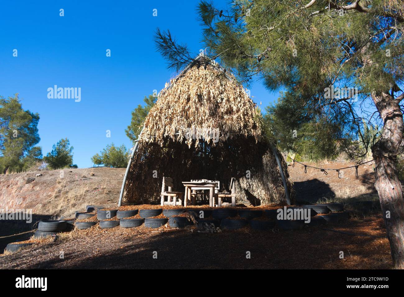 A quaint wooden hut is perched atop a grassy hill, overlooking the lush ...