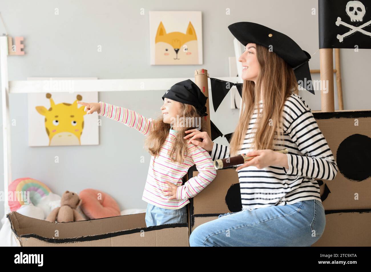 Cute little girl with her mother dressed as pirates playing at home ...