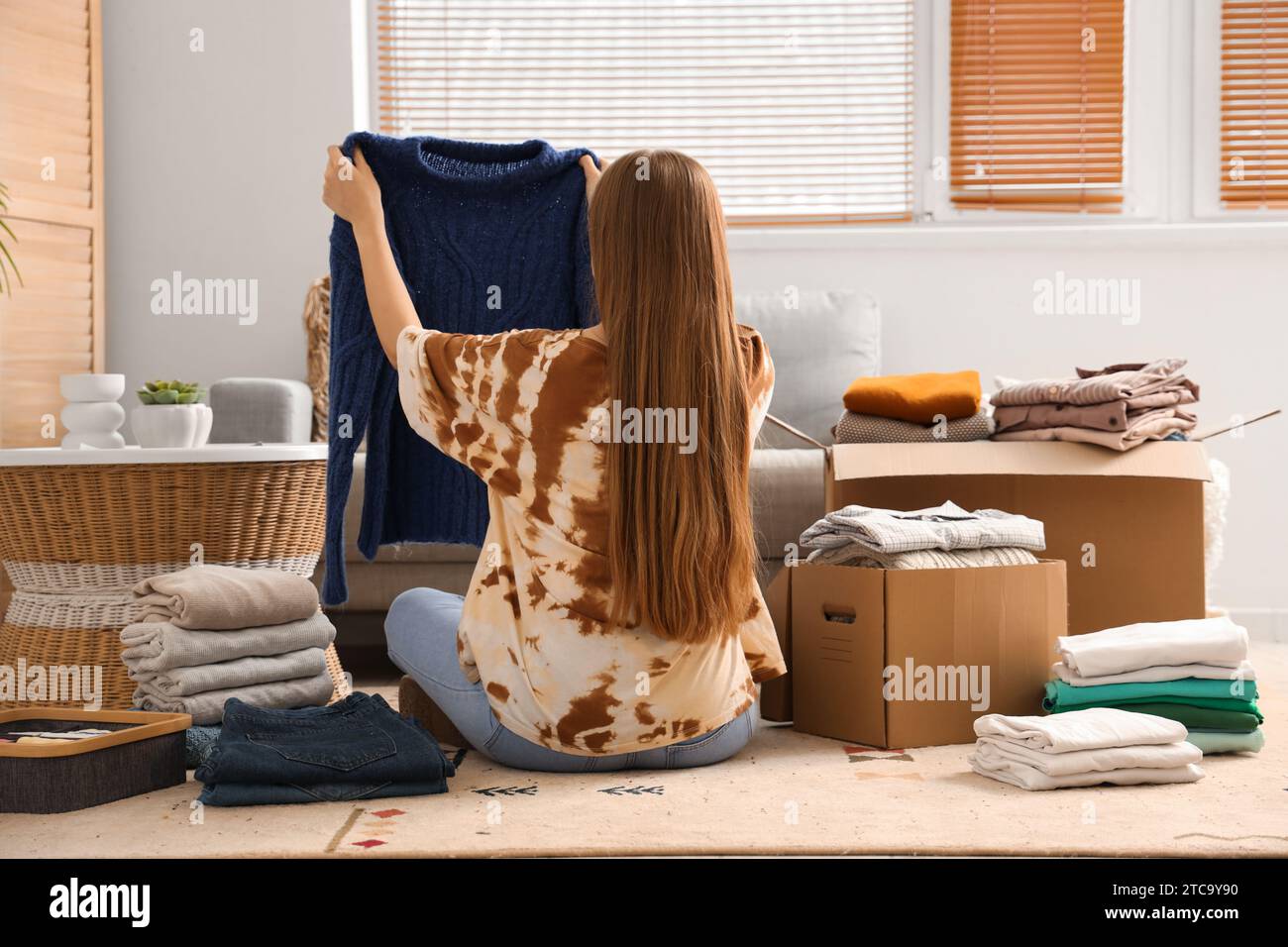Young woman packing clothes into cardboard box in living room Stock ...