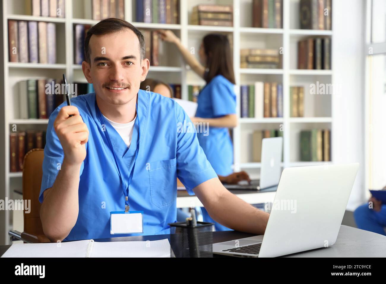 Male medical student studying with laptop in library Stock Photo - Alamy