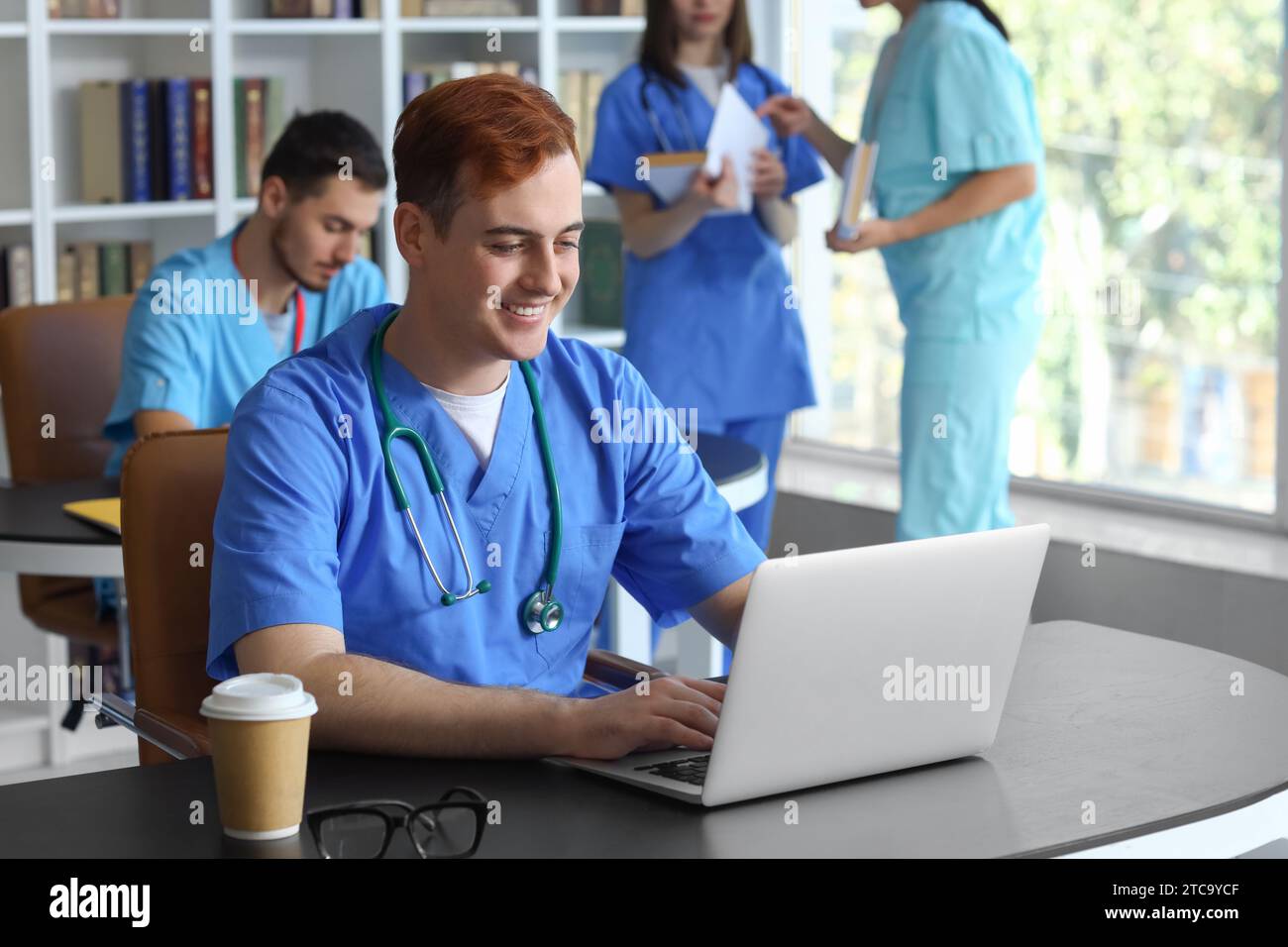 Male medical student studying with laptop in library Stock Photo - Alamy