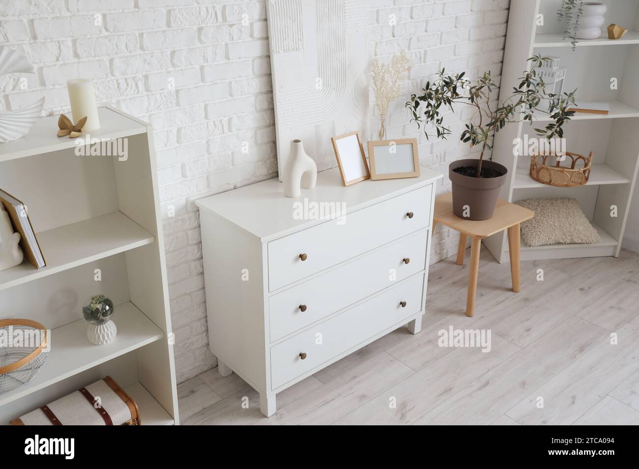Interior of light living room with commode and shelf units Stock Photo ...