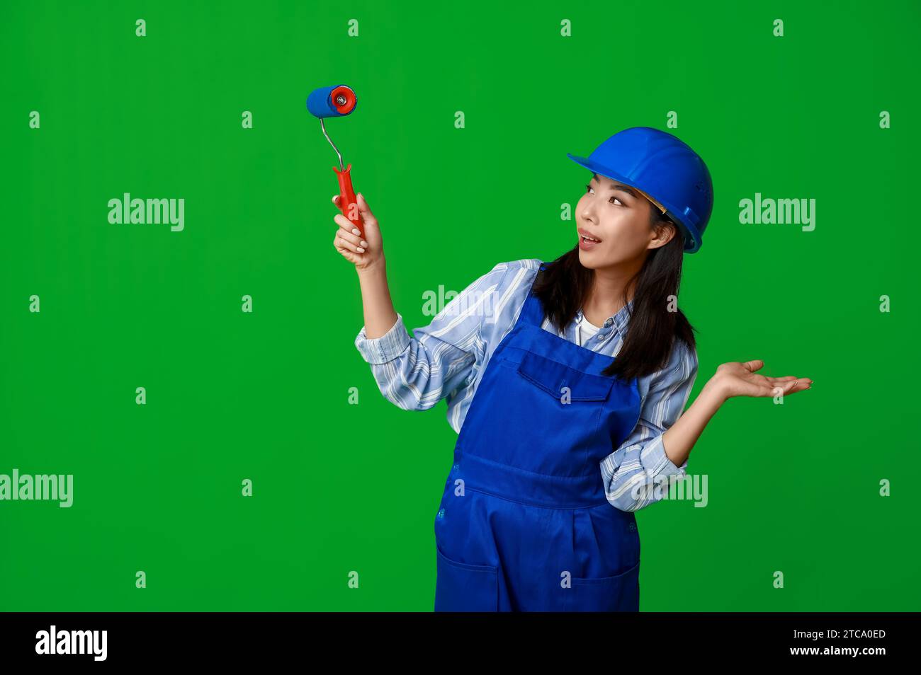 Female Asian shocked painter with roller on green background Stock ...