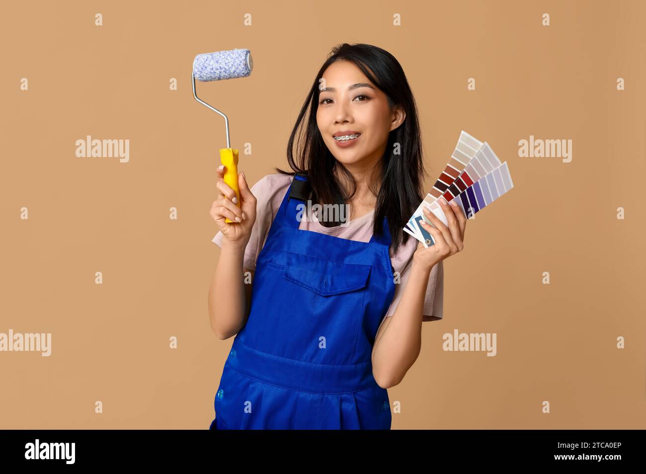 Female Asian painter with paint color palettes and roller on brown ...