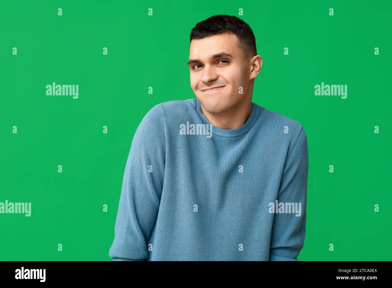 Handsome ashamed young man on green background Stock Photo - Alamy