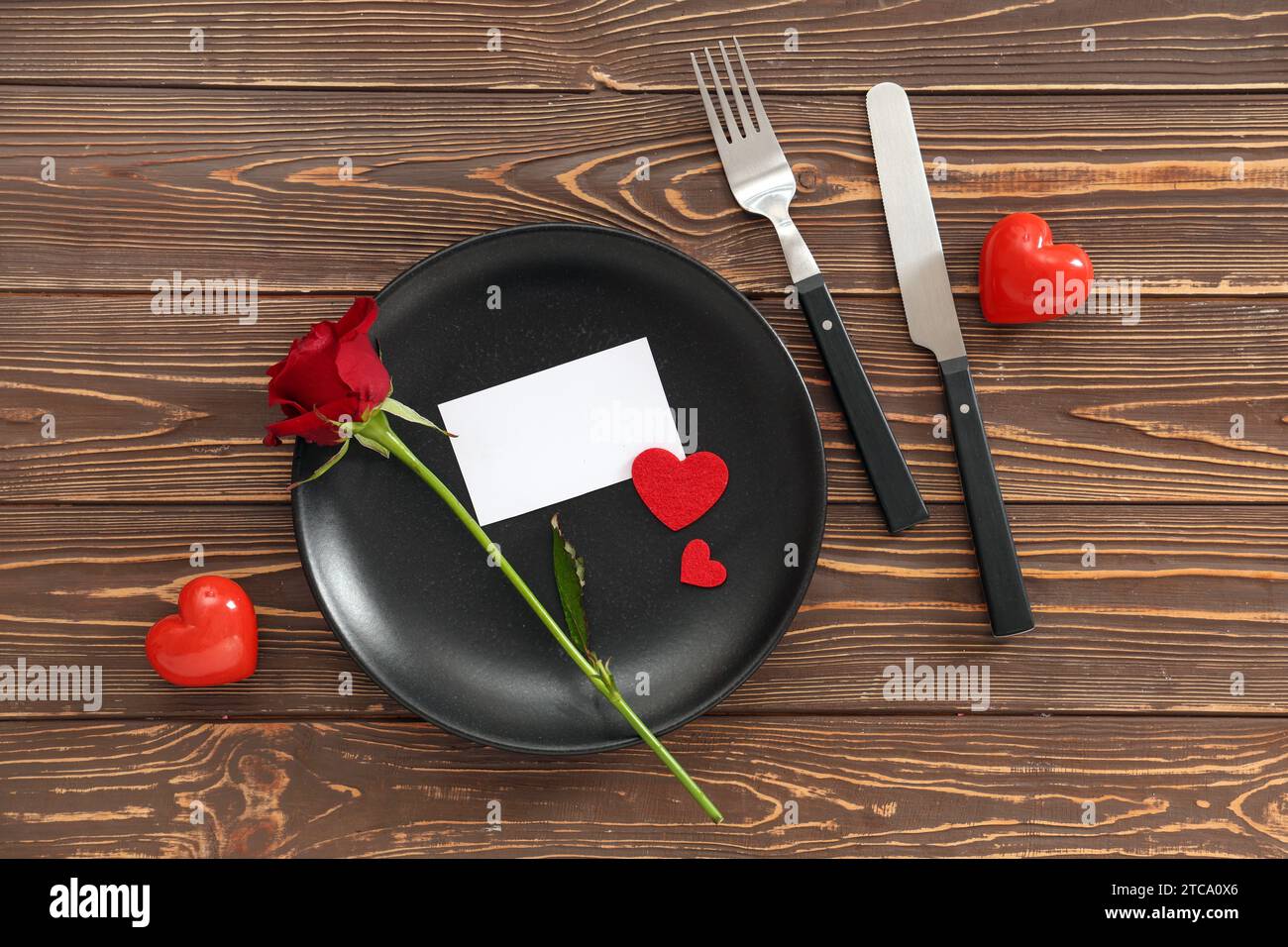 Blank card and beautiful table setting with red rose on wooden ...