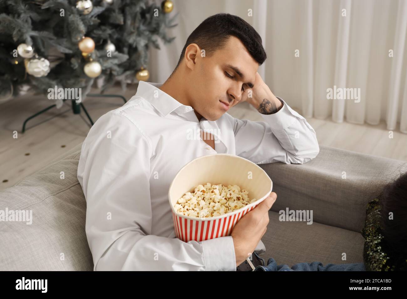 Drunk young man with popcorn sleeping on sofa after New Year party at ...