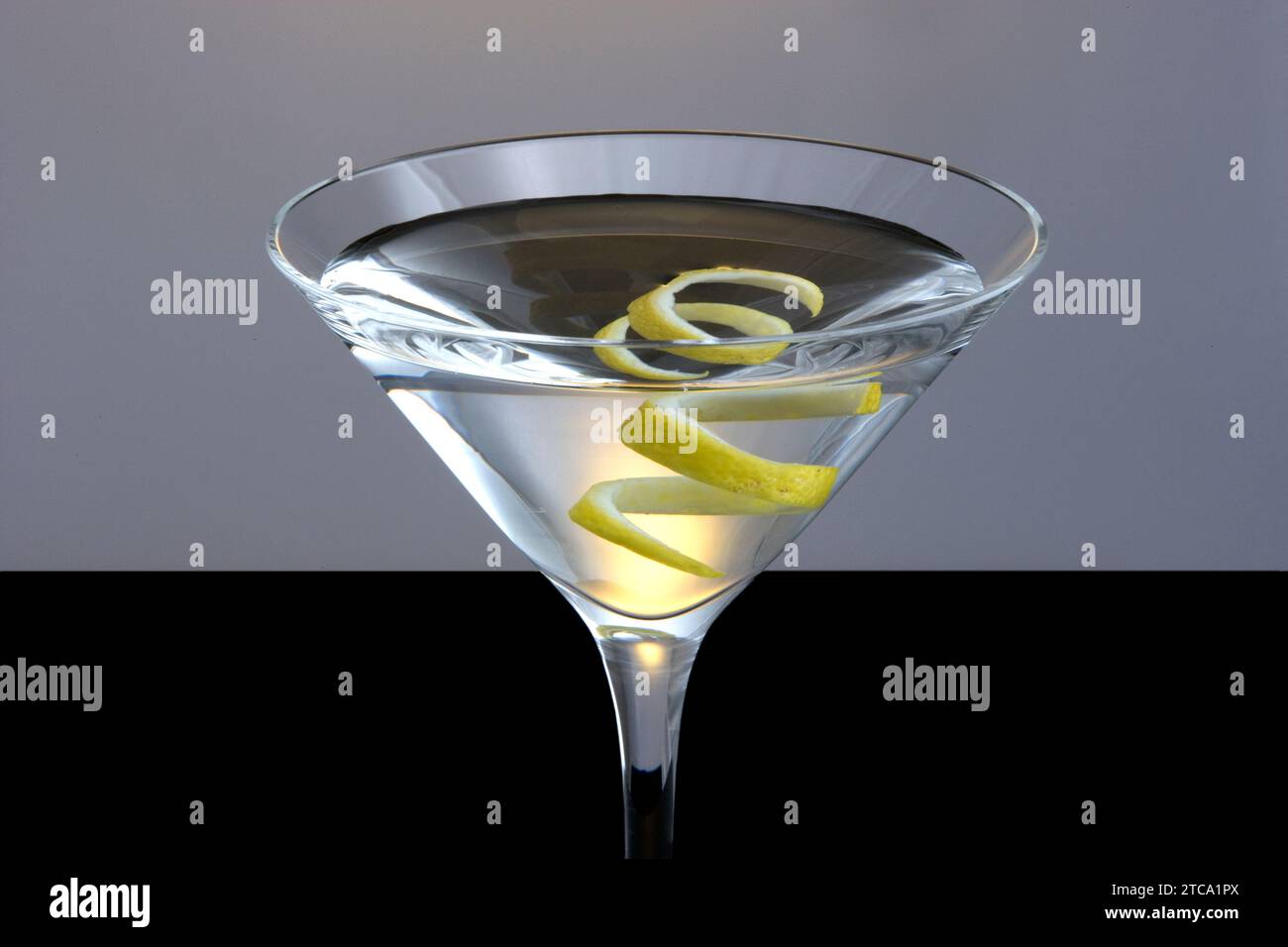 Martini mixed drink with lemon peel garnish in stemware on black and ...