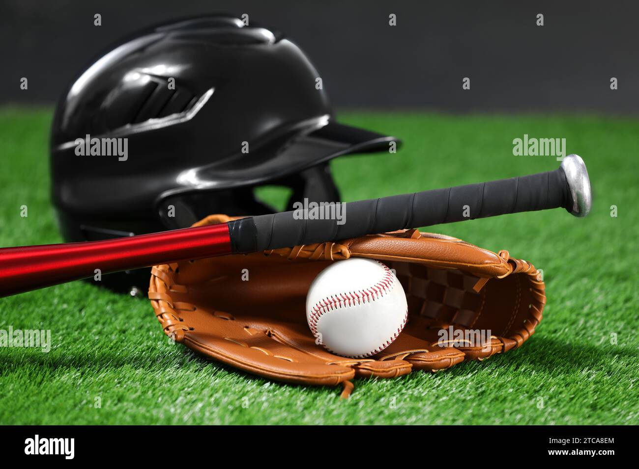 Baseball bat, batting helmet, leather glove and ball on green grass ...