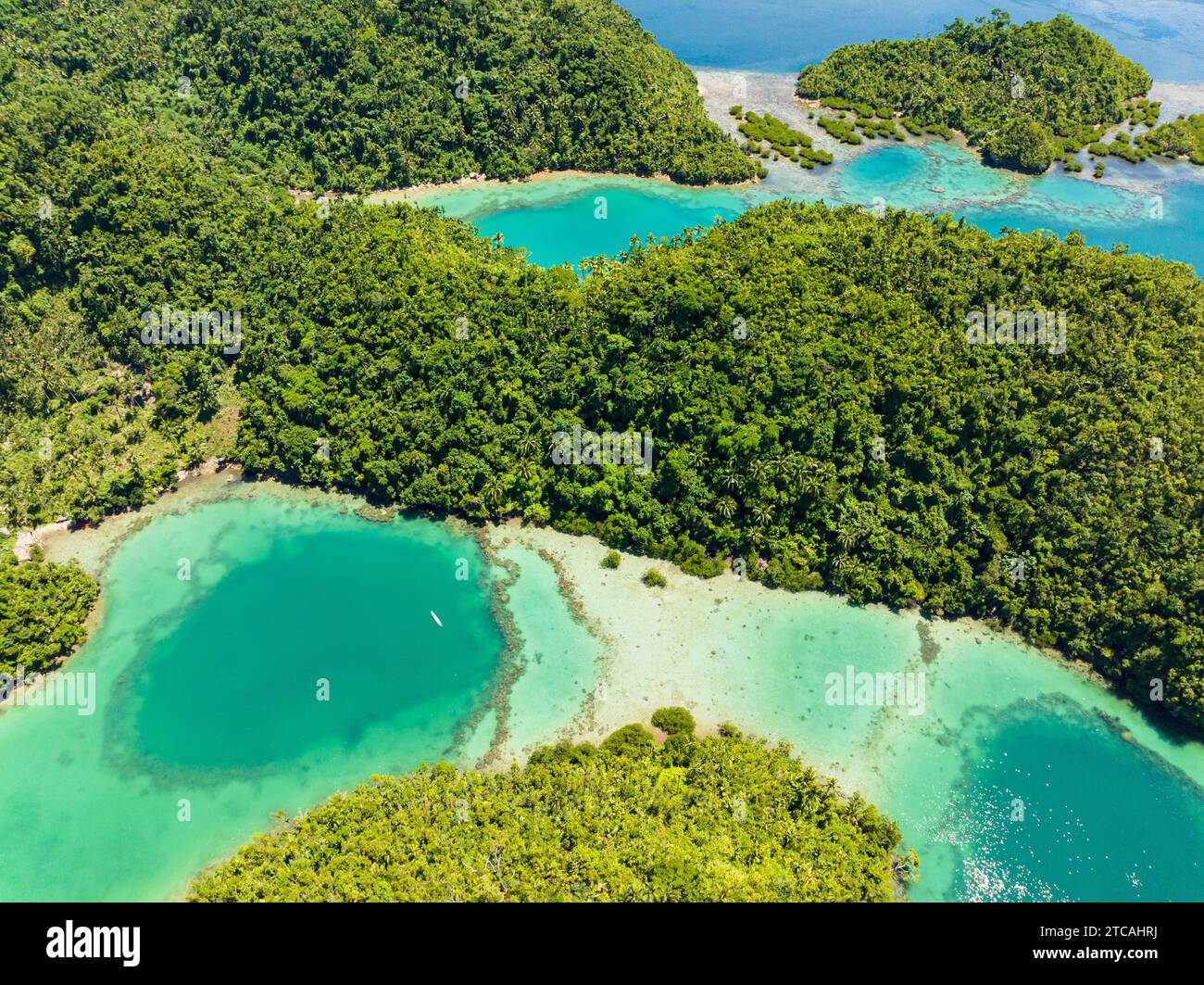 Beach in tropical islet surrounded by turquoise lagoon and mountains ...