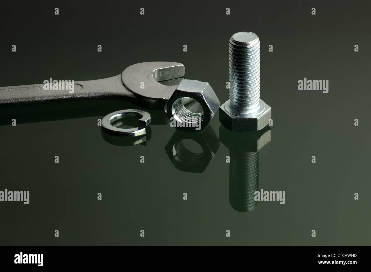 Wrench, bolt, nut and spring washer placed on a reflective surface ...