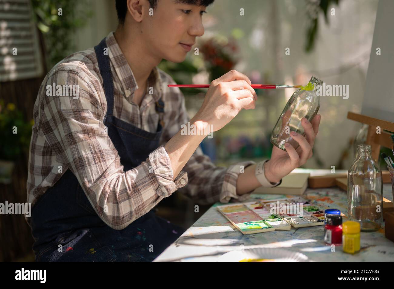 A positive and handsome young Asian man is handcrafting a decorative ...