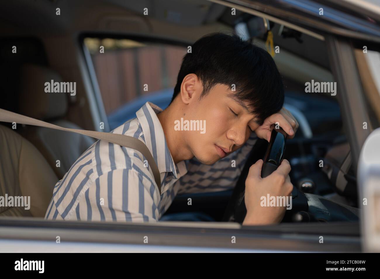 A tired young-adult Asian man is falling asleep in his car after ...