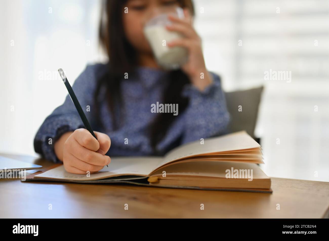 Select focus on hands of Asian school girl doing homework at dining ...