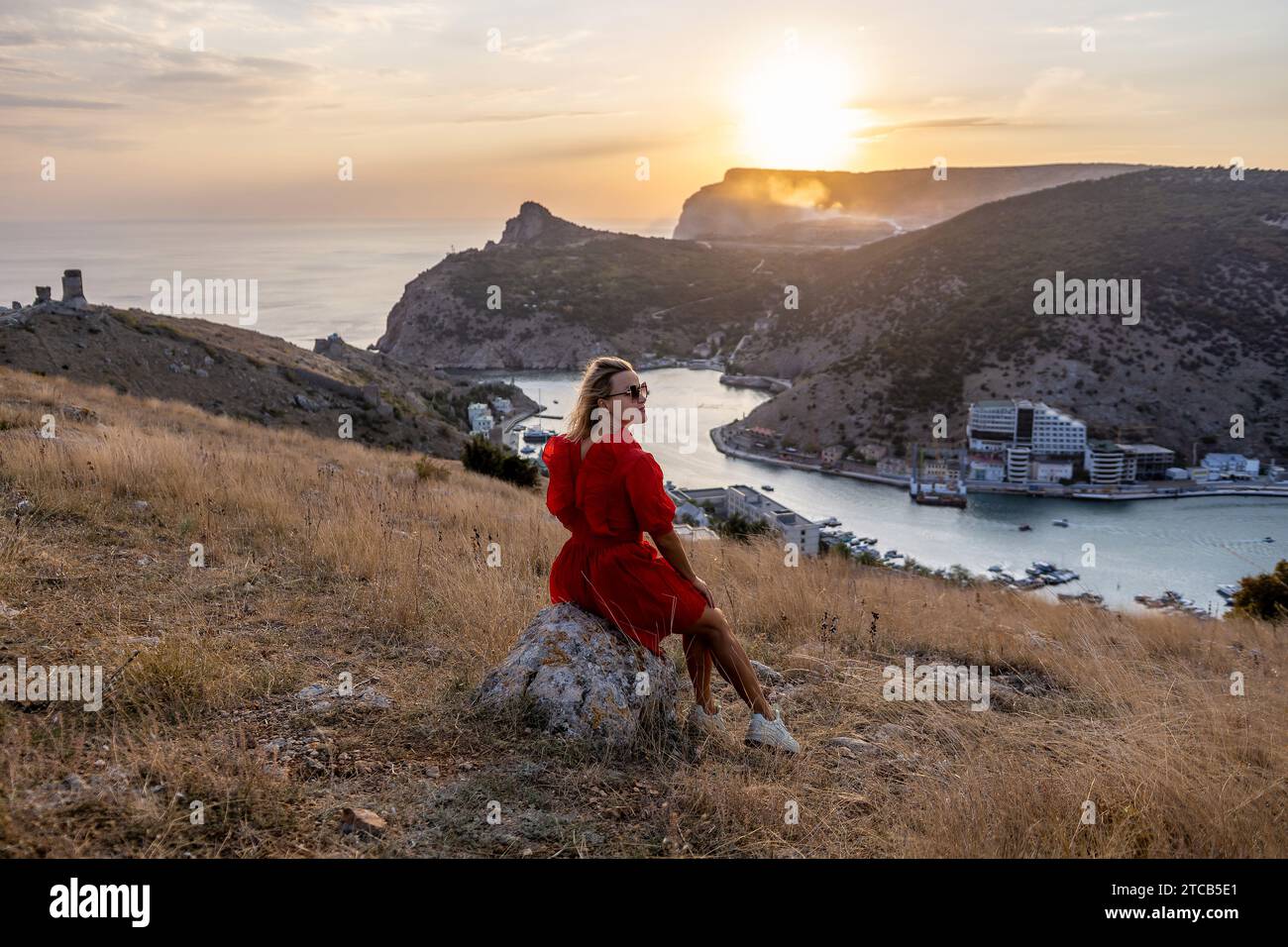 Woman sunset sea mountains. Happy woman siting with her back on the ...