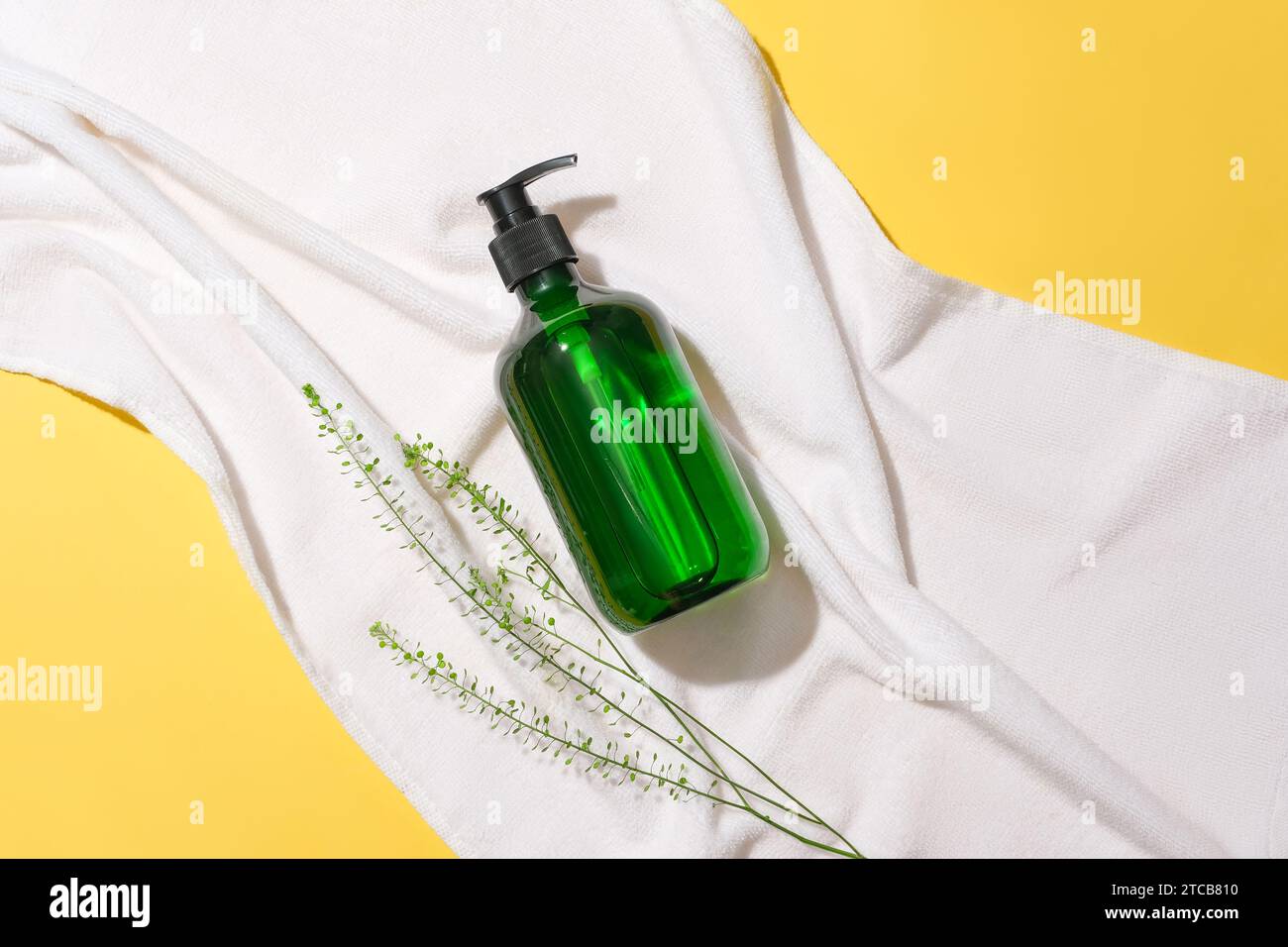 A transparent green shampoo bottle on a white cloth on a yellow ...
