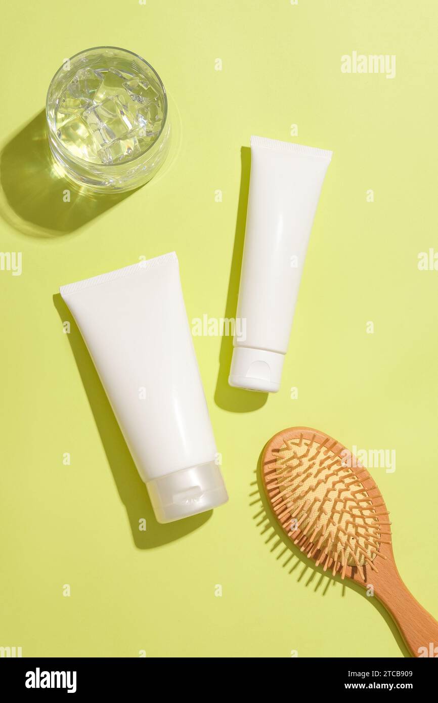 A glass of water, two unlabeled cosmetic tubes and a detangling comb ...