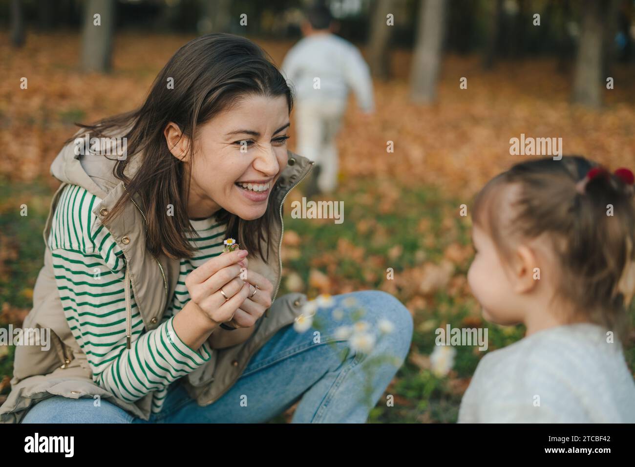 Mother and daughter collecting wild flowers in autumn forest. Young mother and her little ...
