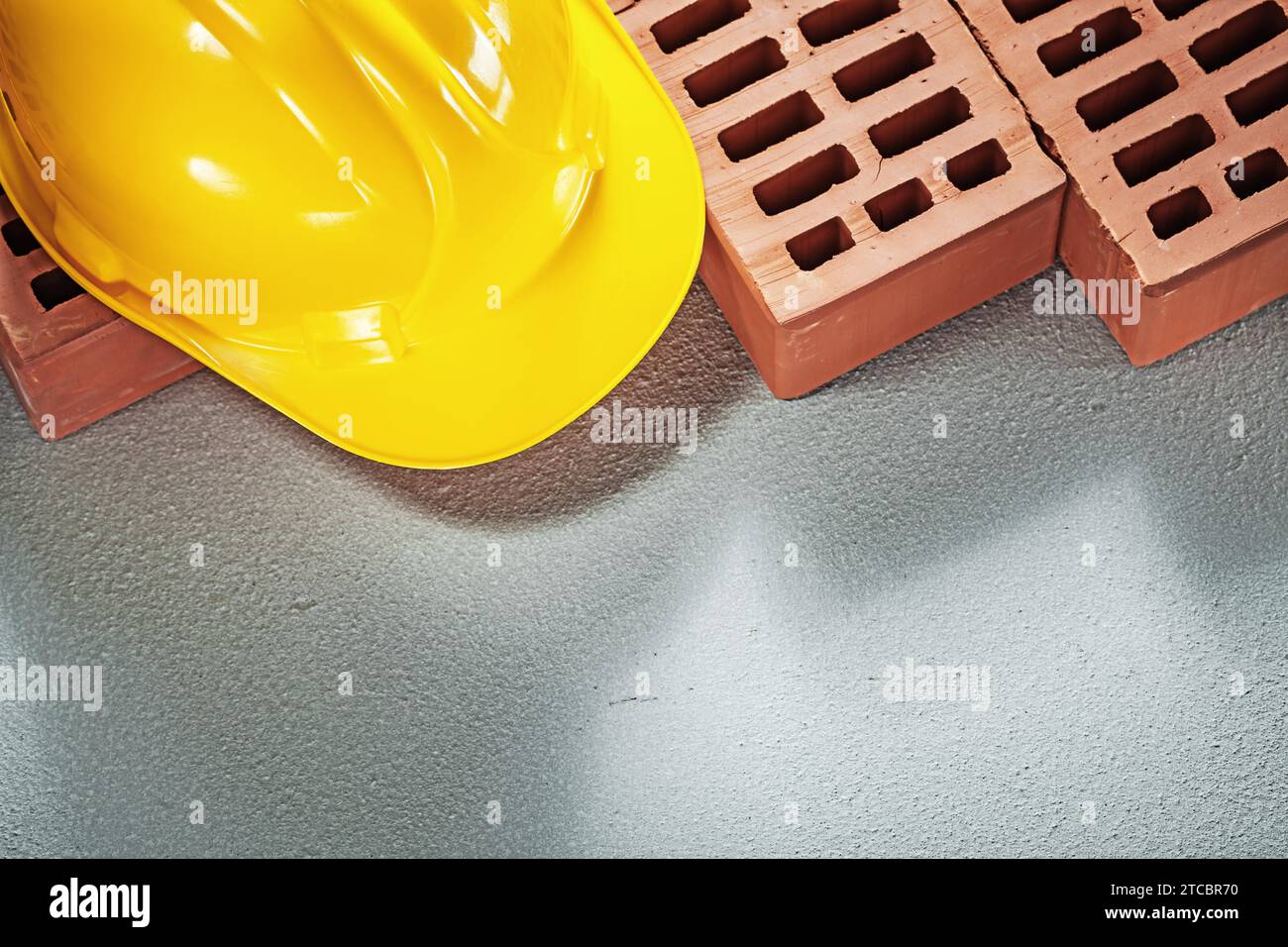 Red building brick safety hard hat on concrete background construction ...