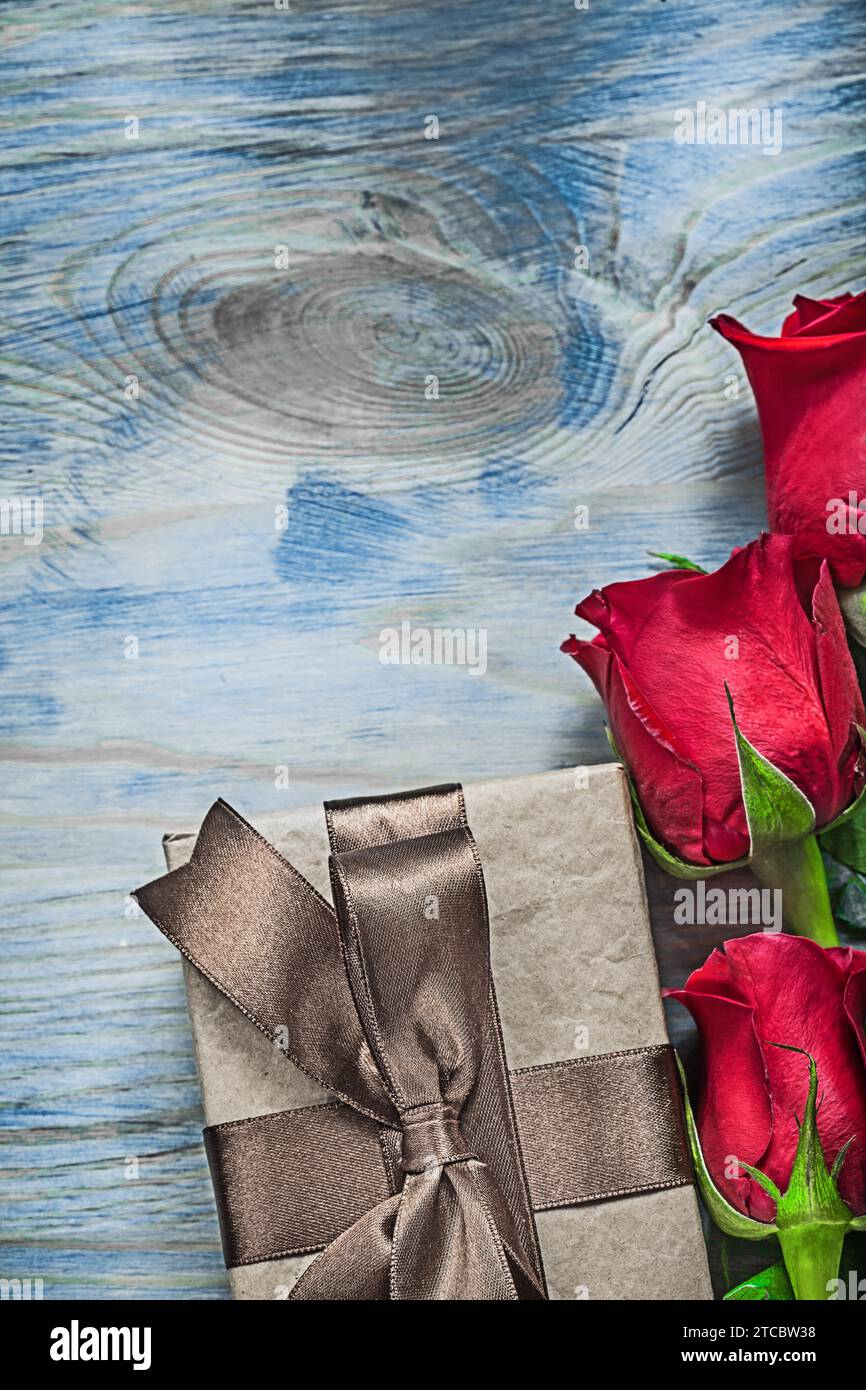 Composition of the wrapped gift box red roses on wooden board ...