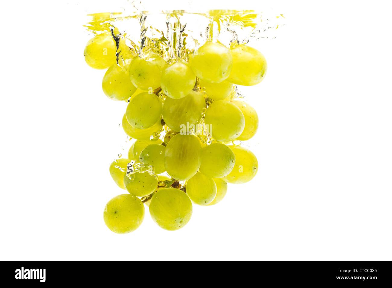 Bunch of green grapes sinking into crystal clear water with air bubbles ...