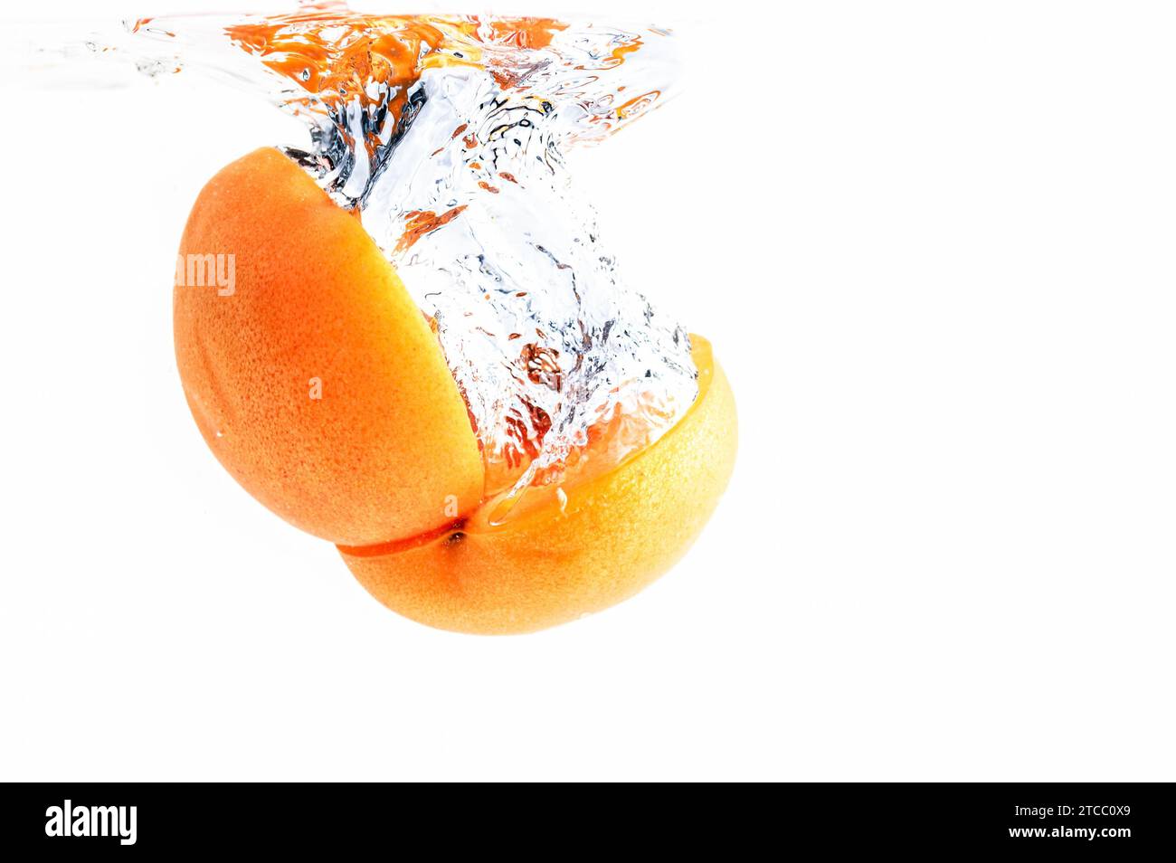Fresh apricot spitted in half falling in water splash. Half of fruit in ...