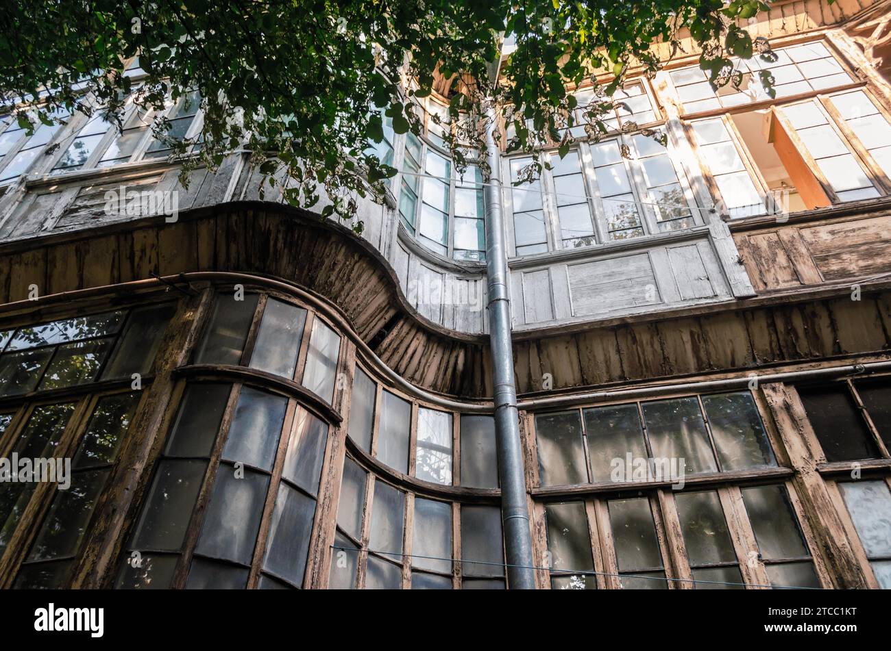 Windows of old tall house with green leaves of tree branch in Tbilisi ...