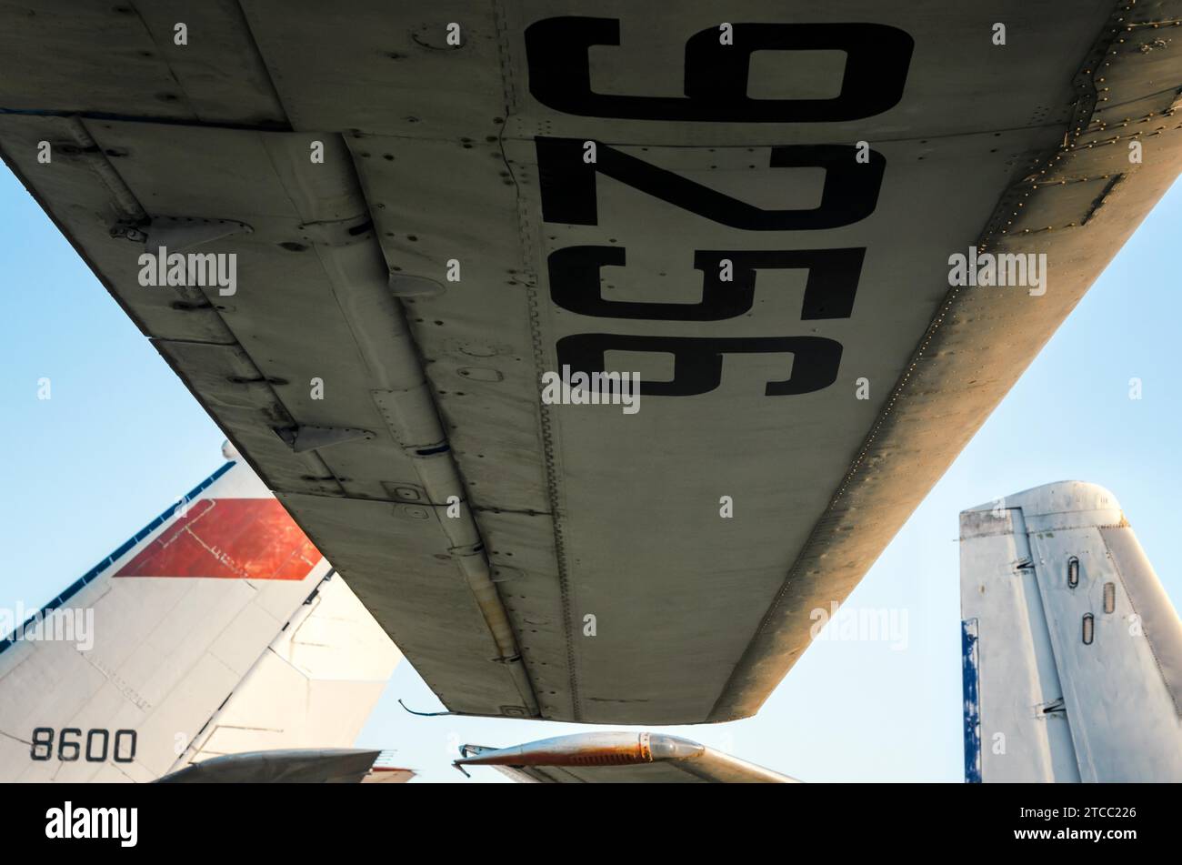 Wing with tail number on the background of airplanes and blue sky close ...