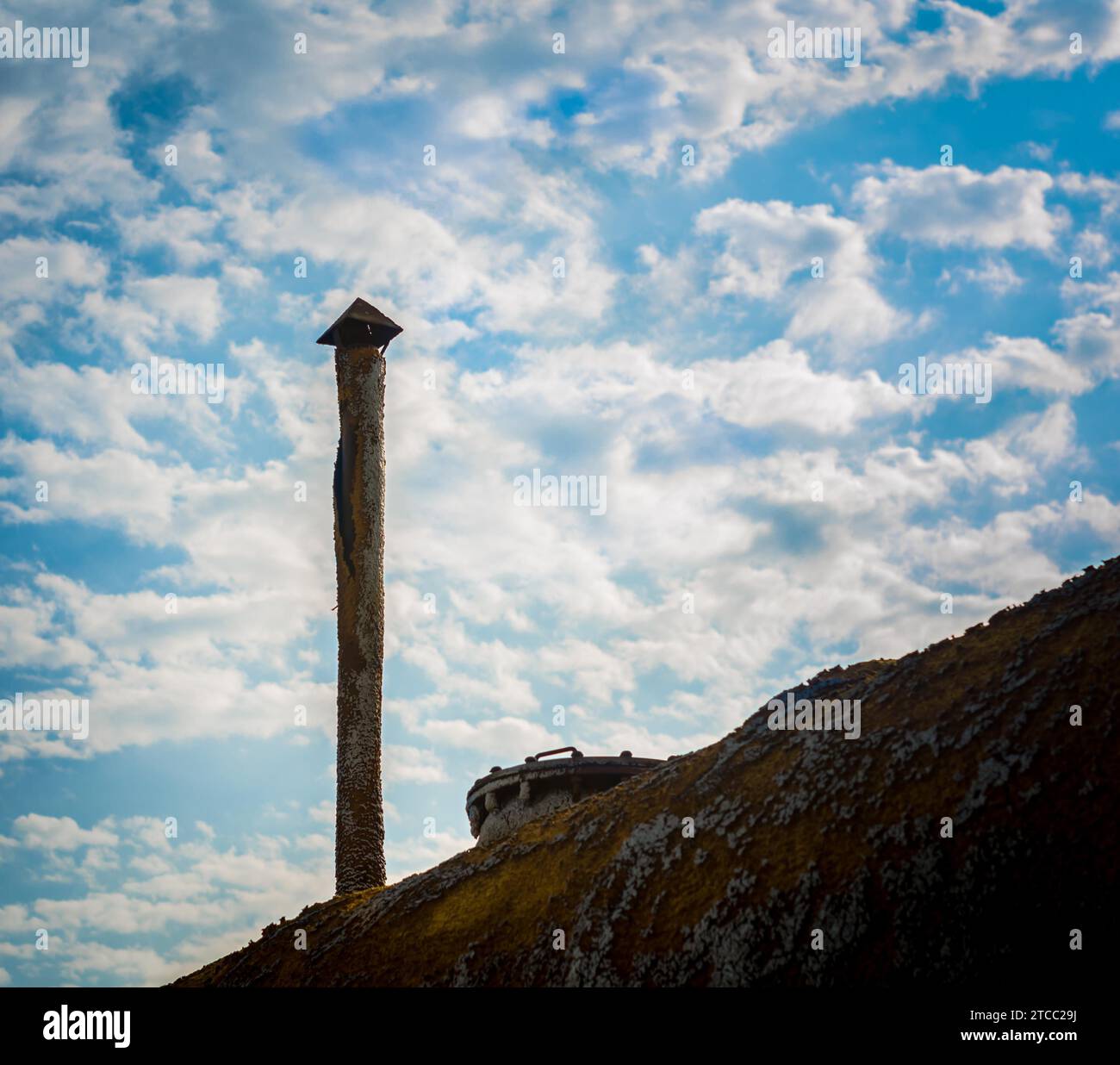 Old rusty chimney pipe and rusty tank hatch against the blue sky and ...