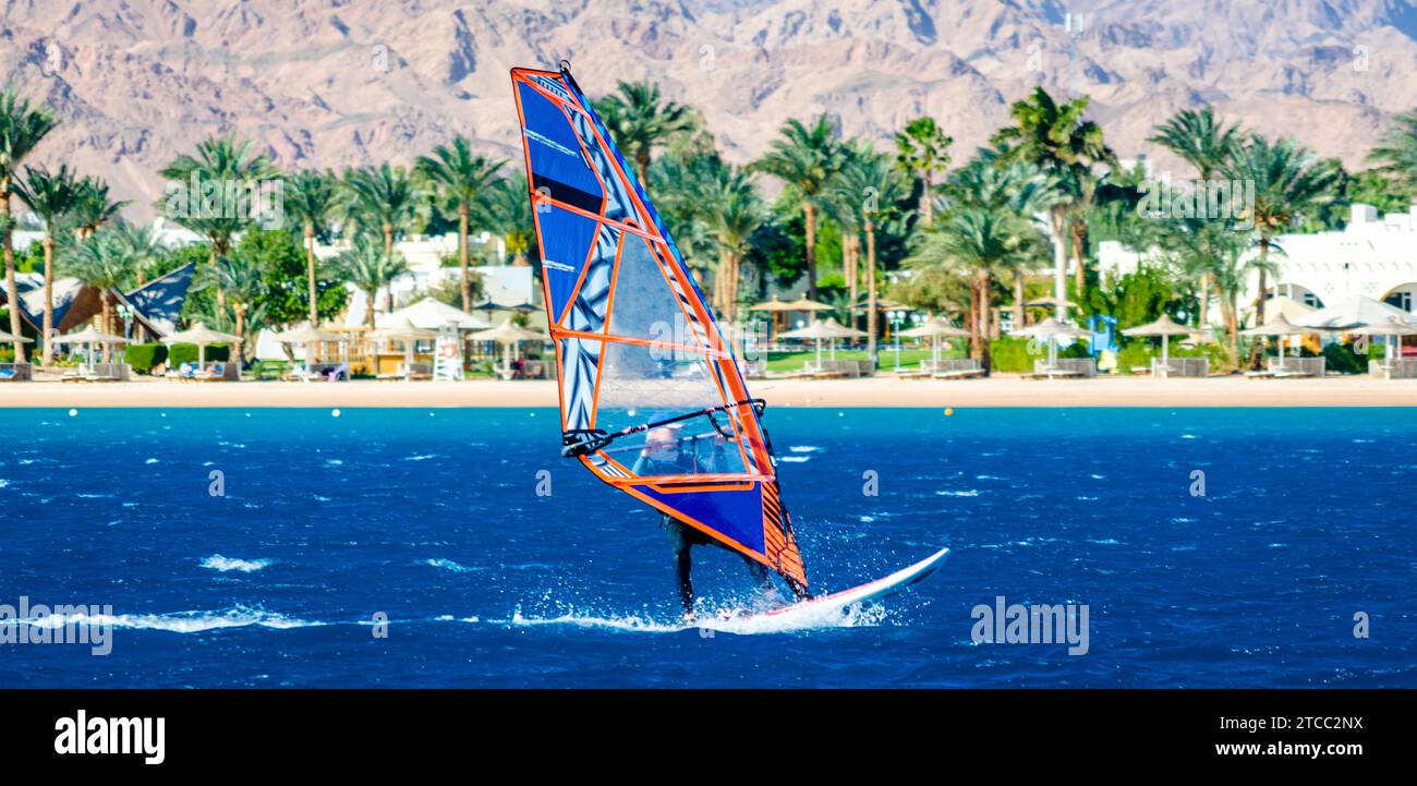 Windsurfer rides on the background of the beach with a hotel and palm ...