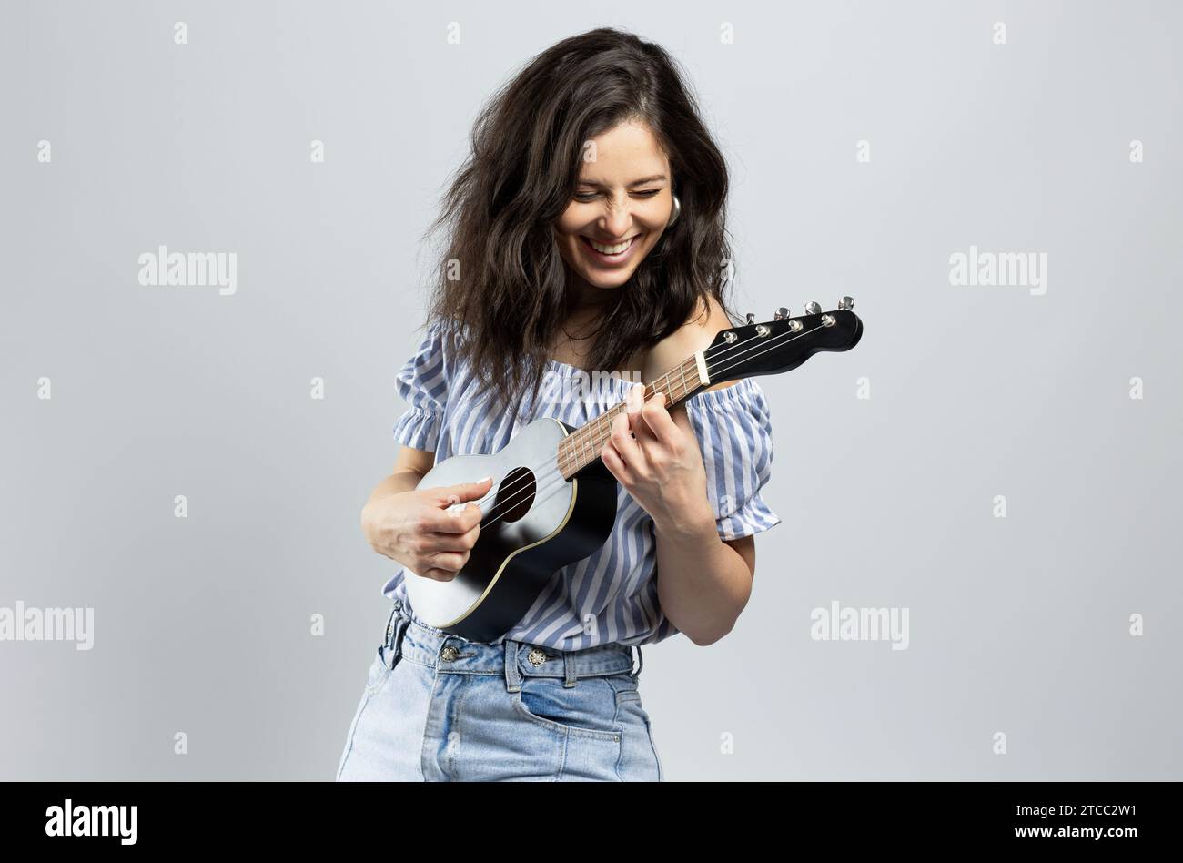 Attractive Brunette Woman Playing Ukulele Isolated On Gray Background