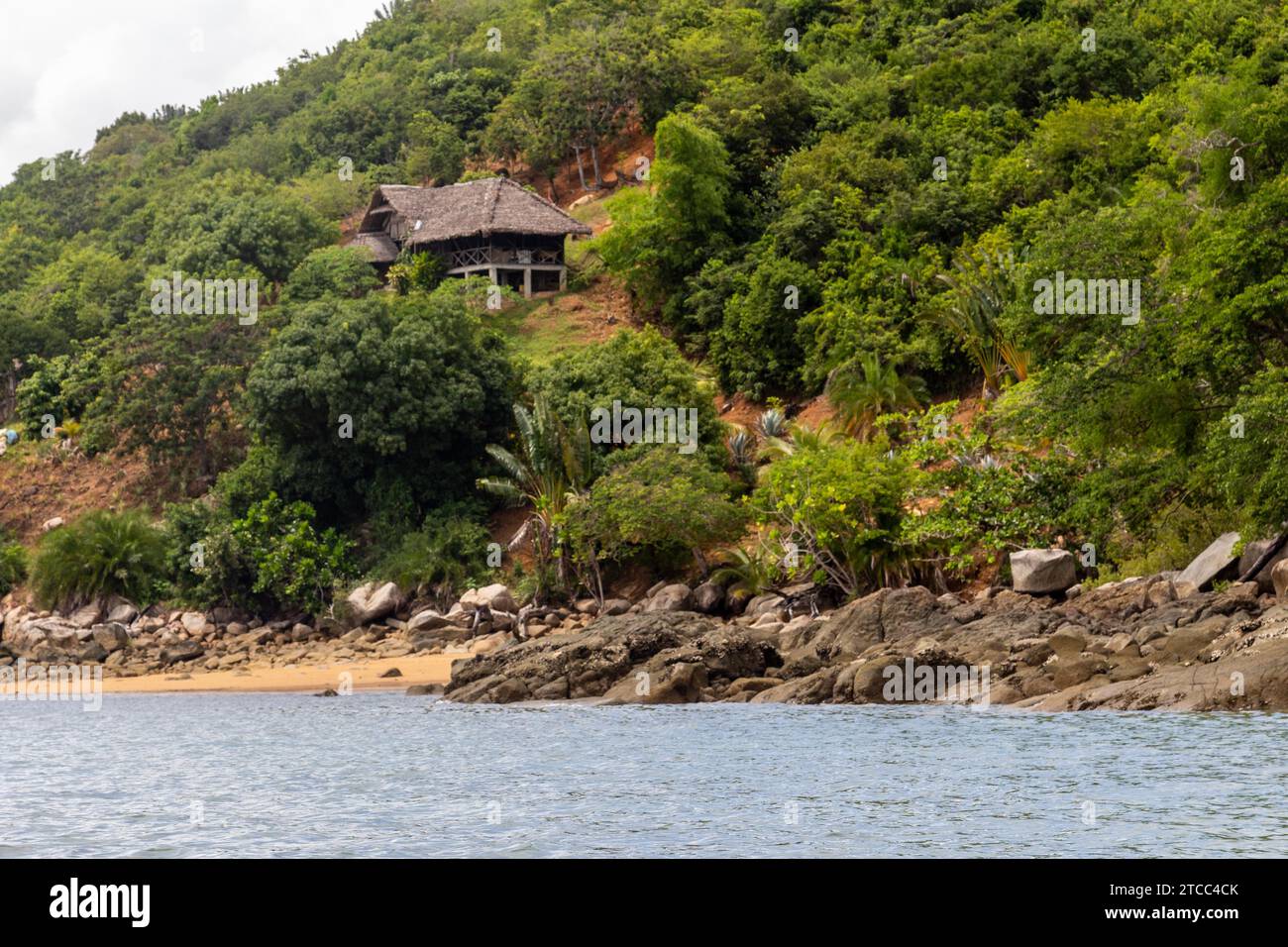 Beach with palm trees and wooden cottage, green mountains at Lokobe ...
