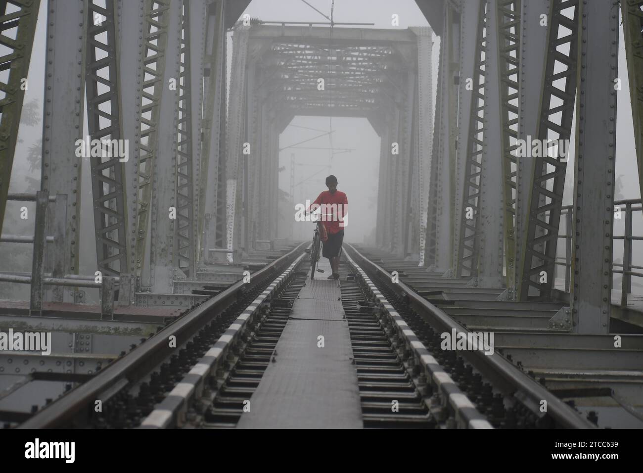 Assam. 12th Dec, 2023. A man pushing a bicycle walks on a railway ...