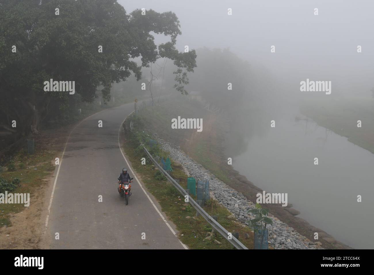 Assam. 12th Dec, 2023. A man rides a motorcycle amid fog on a cold ...