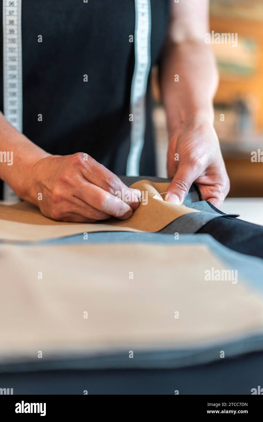Fashion designer putting pins into pattern and fabric. Vertical shot ...