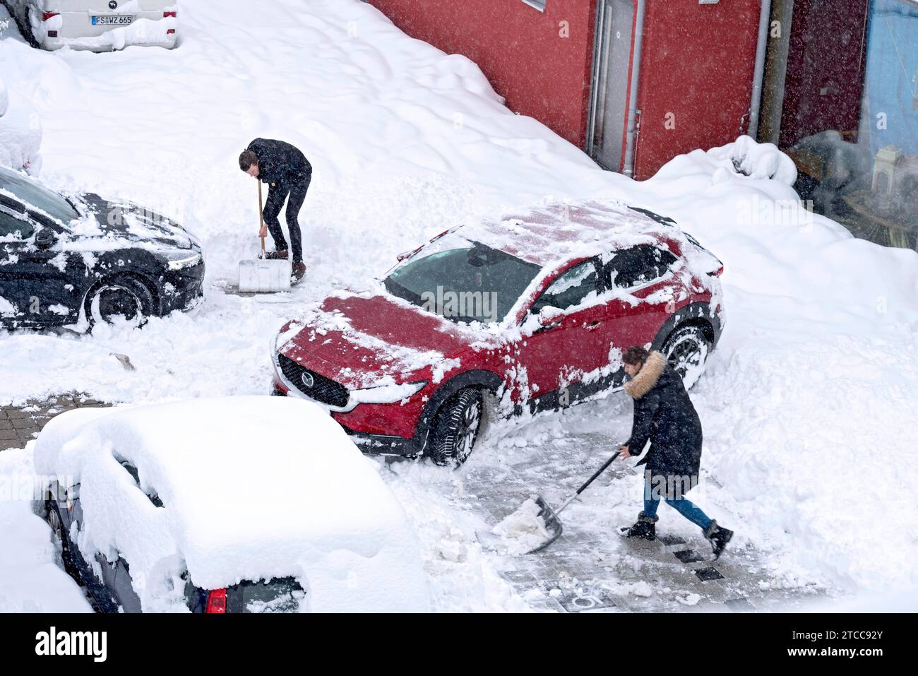 Man and woman shovelling snow on car park, car, car, snowed in, fresh ...