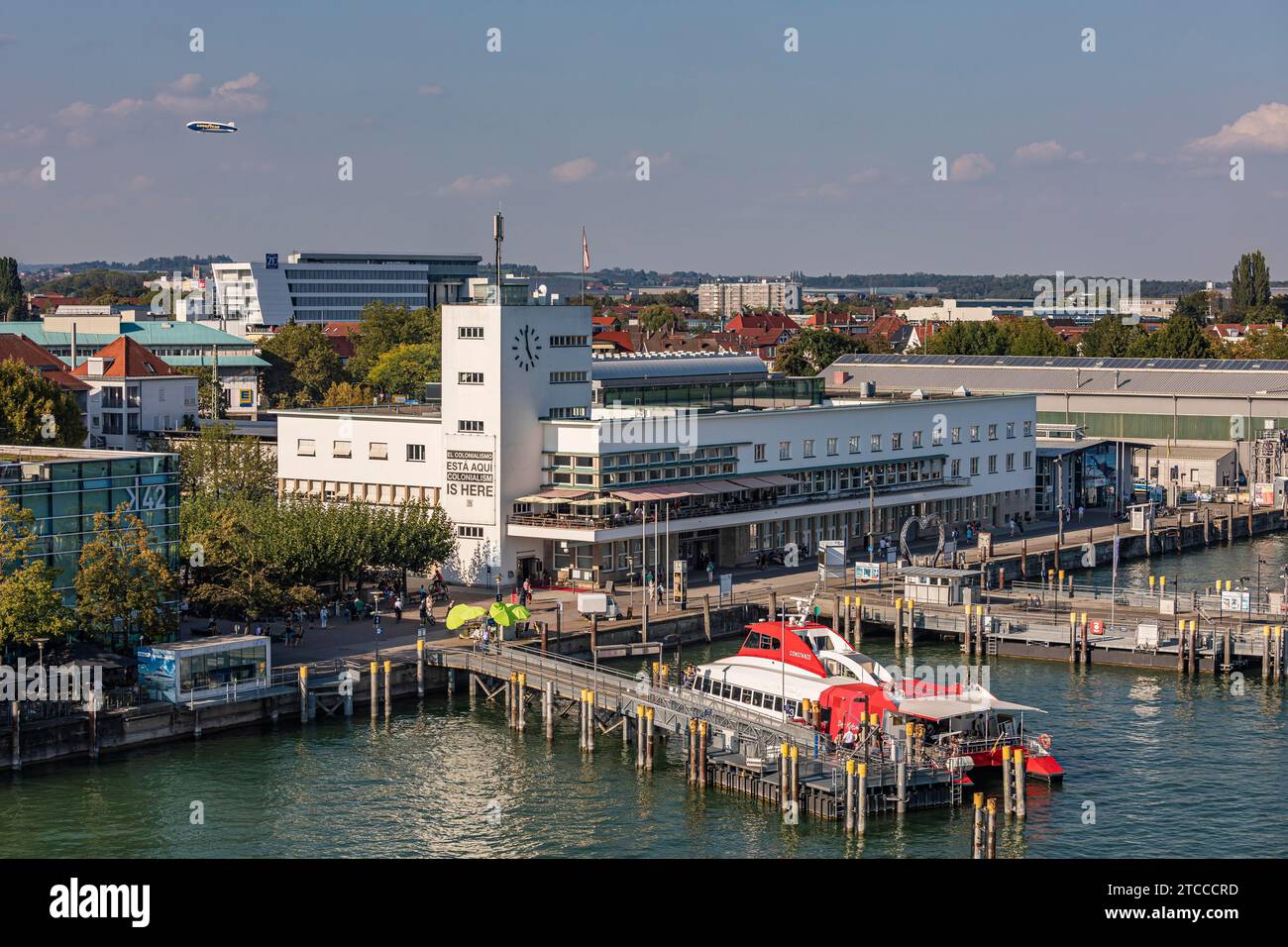 Zeppelin NT in the sky and ferry in front of the Zeppelin Museum in the ...